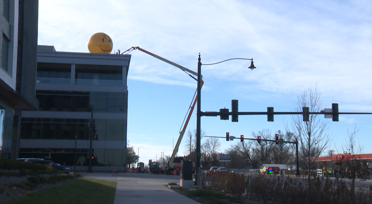 Walmart hoists 16-foot smiley face sculpture on the roof of Sparky Building