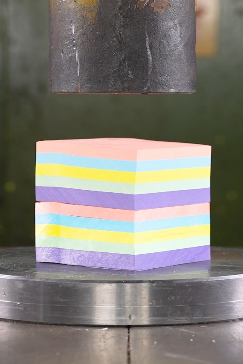 Colorful sticky notes get crushed under hydraulic press