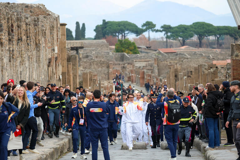 Jackie Chan carries the Milan Cortina Olympic torch through the ruins ...