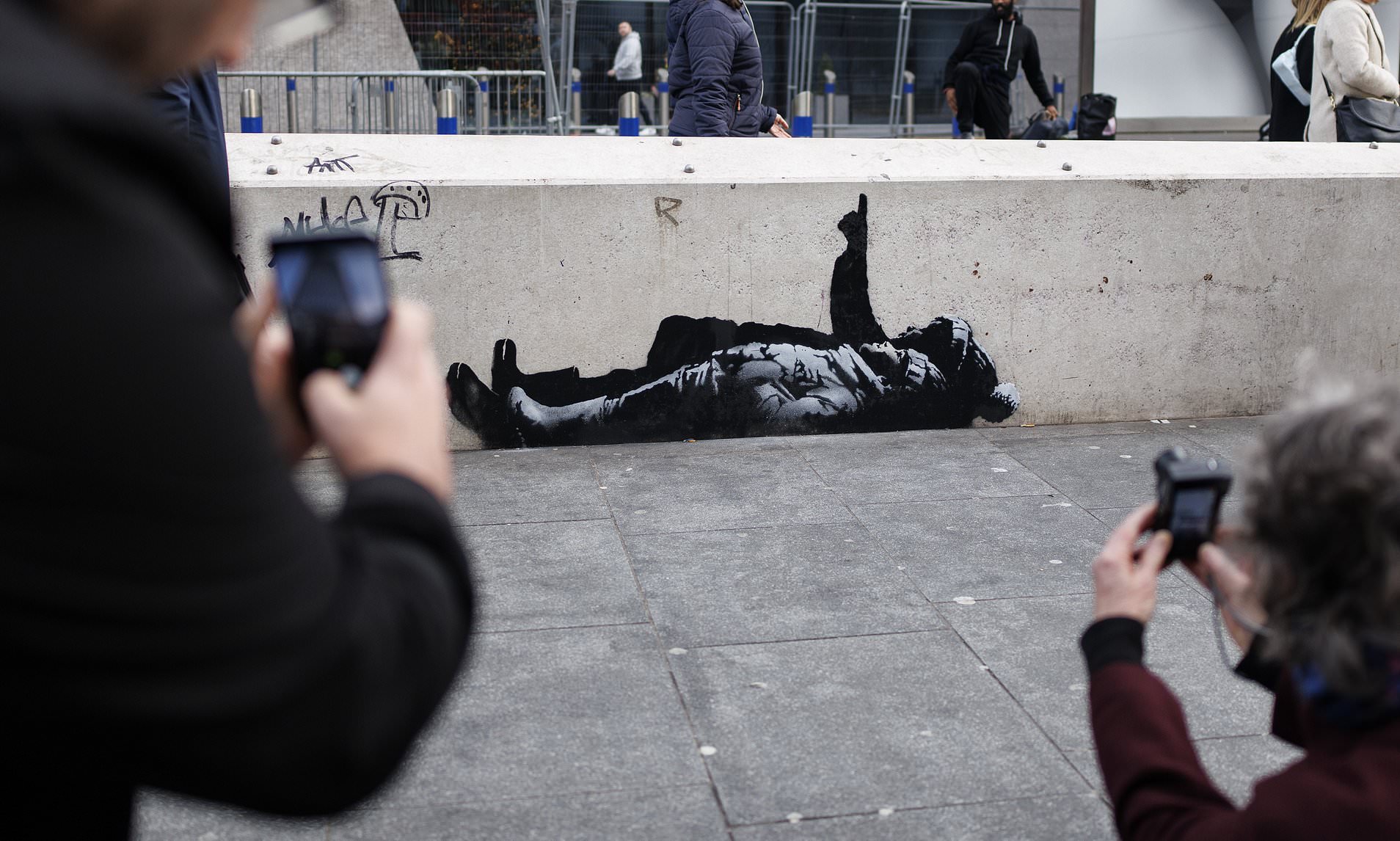 Banksy unveils new artwork of people lying on a street and looking up ...