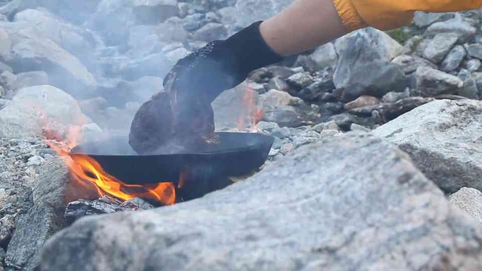 Cooking a monster steak on a stone over fire
