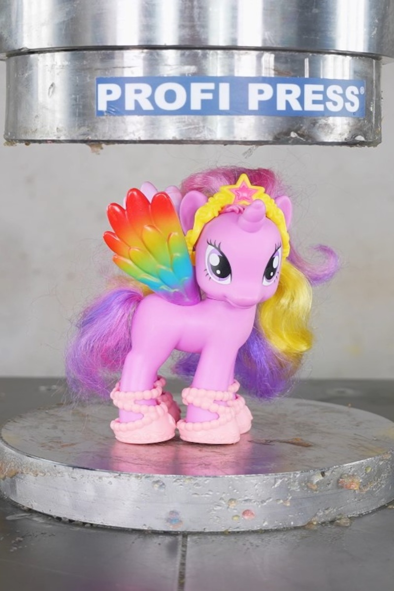 La licorne arc-en-ciel en peluche fait face à la presse hydraulique
