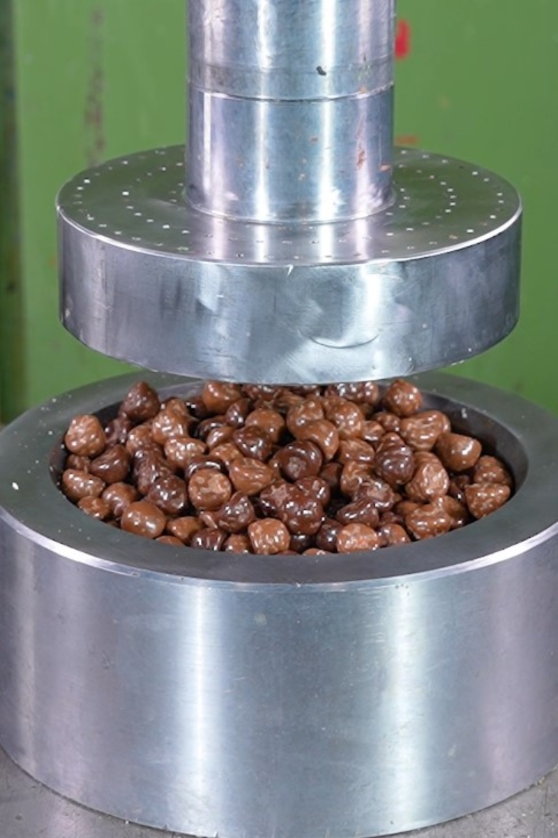 Crushing chocolate-coated nuts under the press