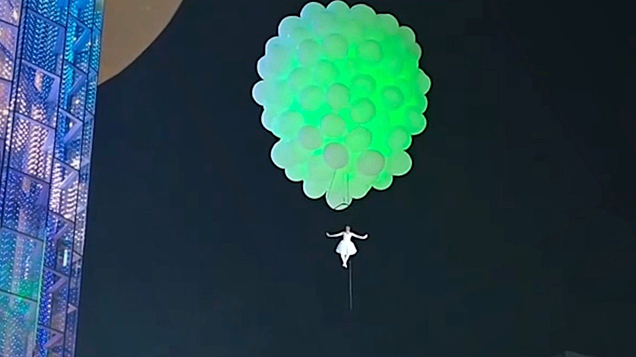 Performer dangles from balloons for 'space ballet' performance