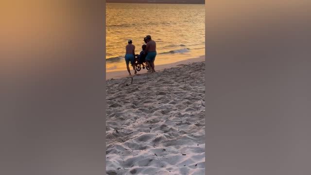 Woman in wheelchair enjoys a sunset view from the ocean shore