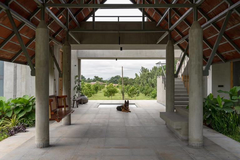 Concrete columns frame open living spaces of Indian home by Taliesyn