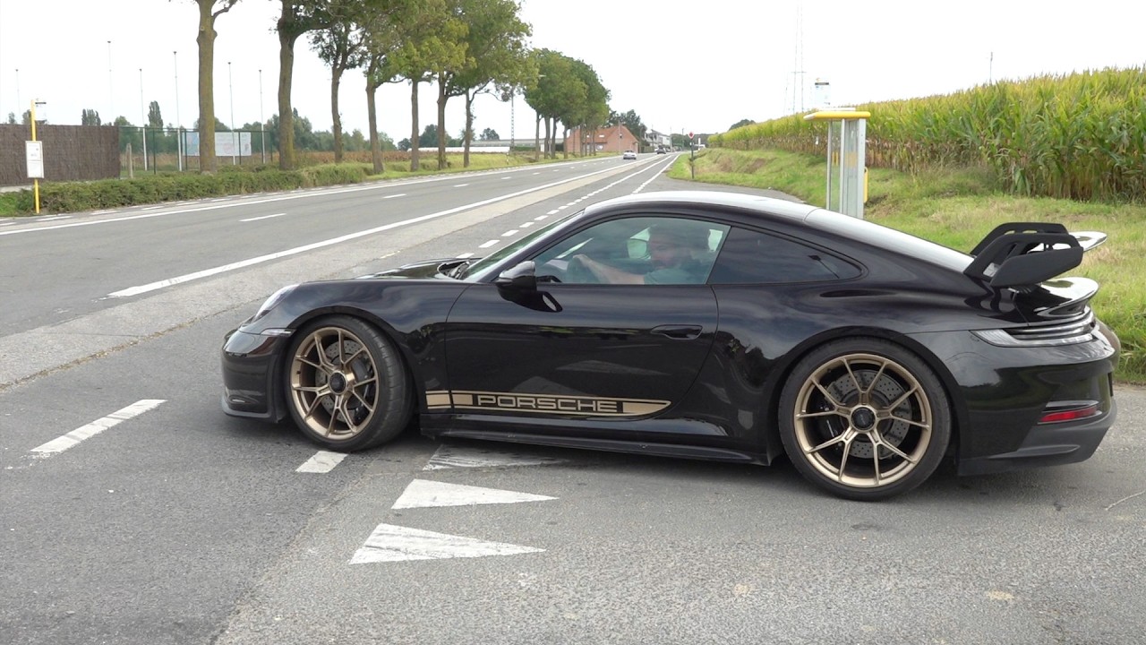 A black Porsche 911 accelerating through a rural area