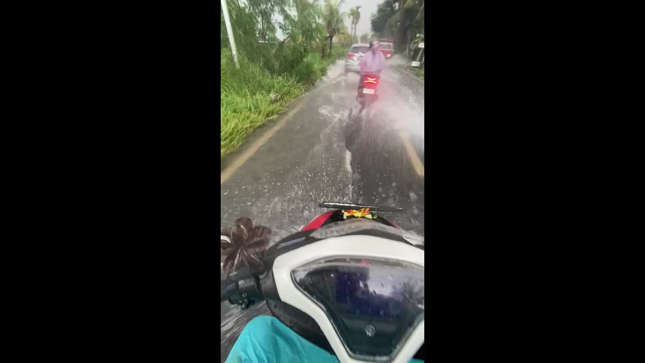 Motorcycle rider drenched by driver speeding through puddle