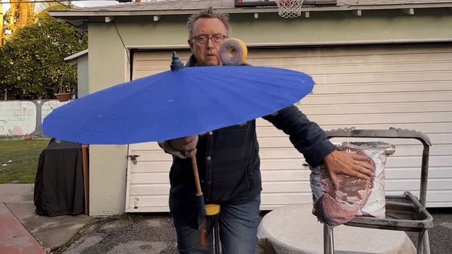Unicycling juggler expertly rolls donut on umbrella