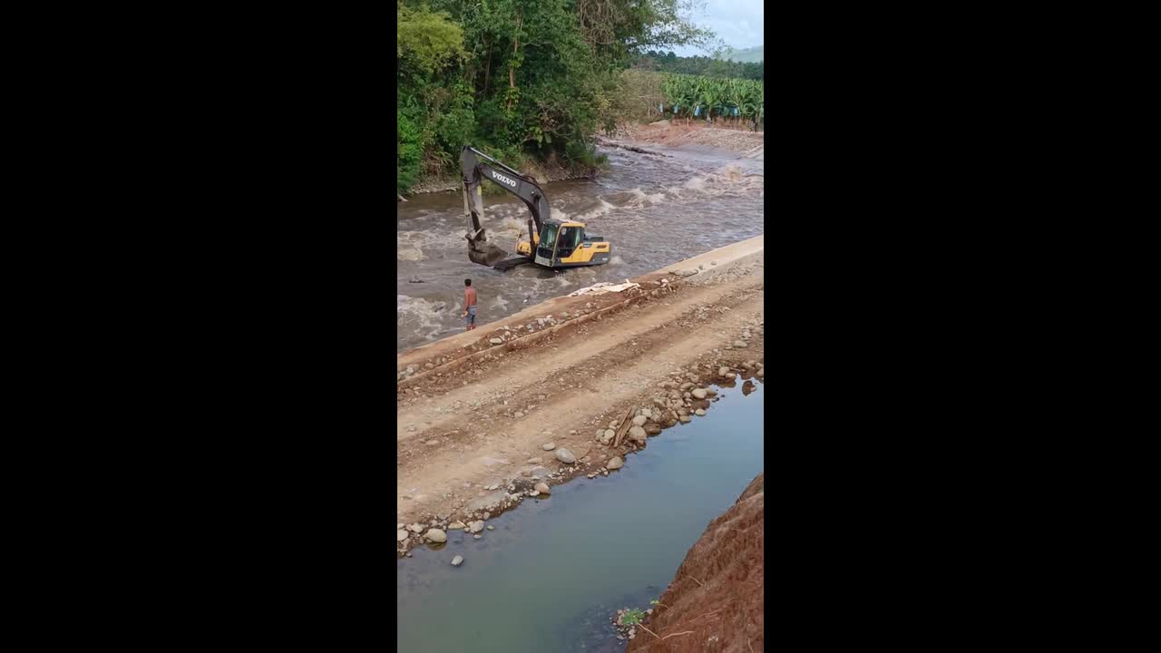 Excavator and driver swept away by fast-flowing muddy river