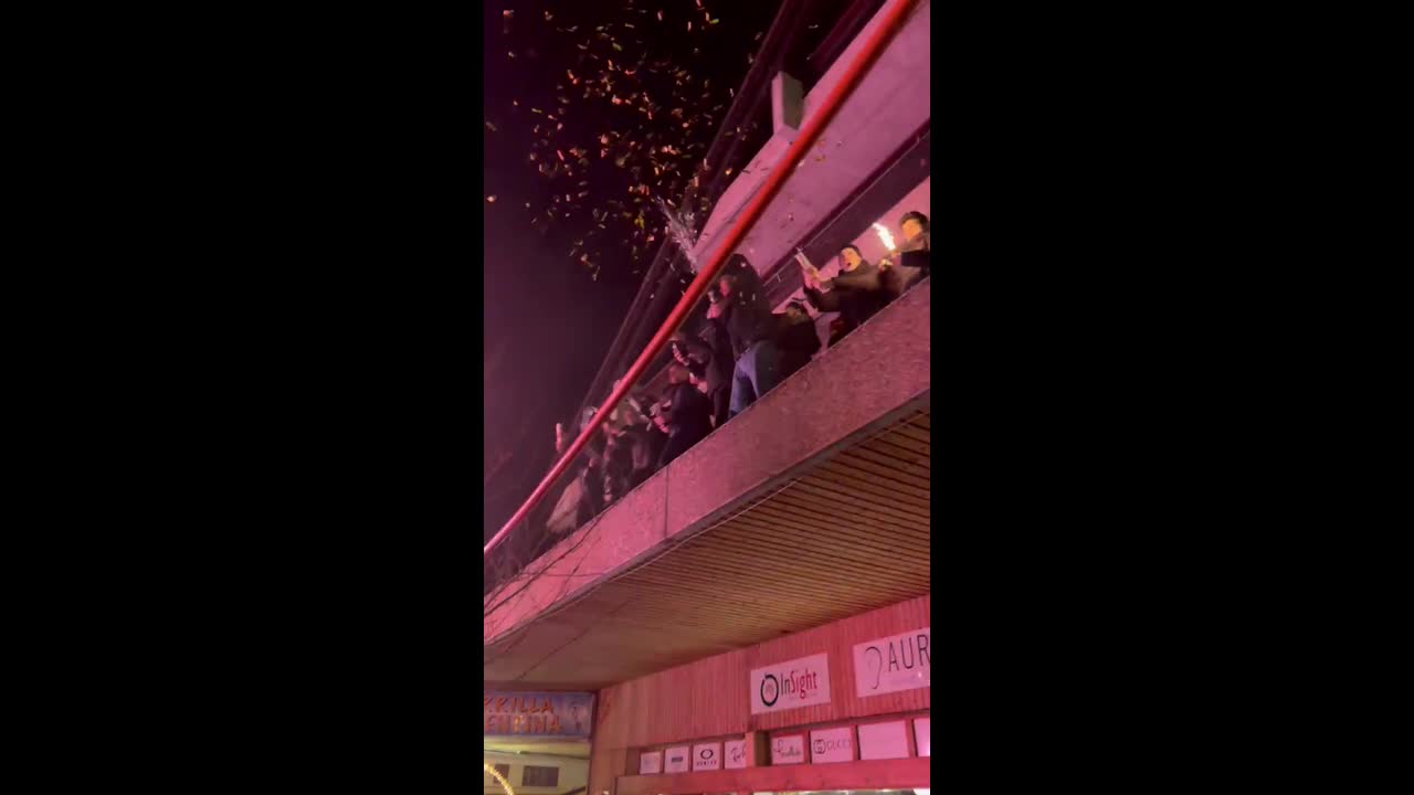 People celebrating on a balcony and releasing party poppers, creating a ...
