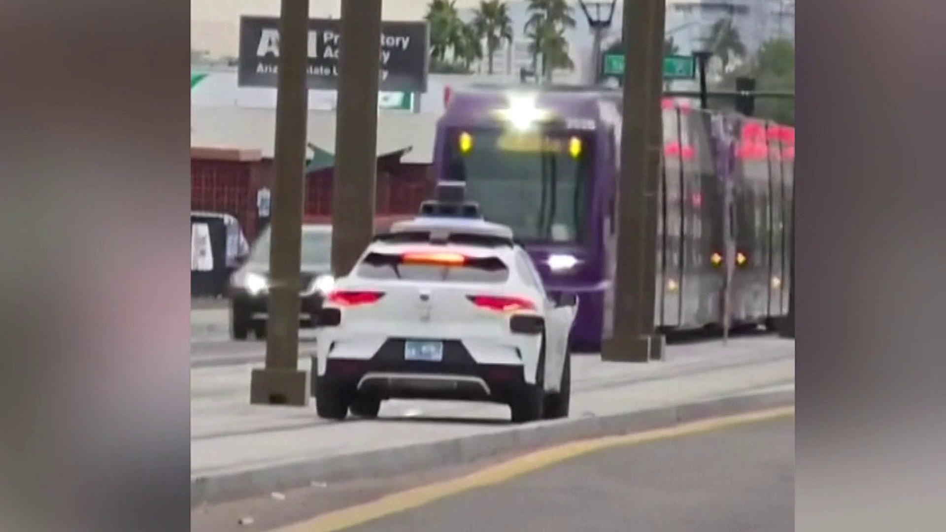 Waymo car seen driving on light rail train tracks in Phoenix