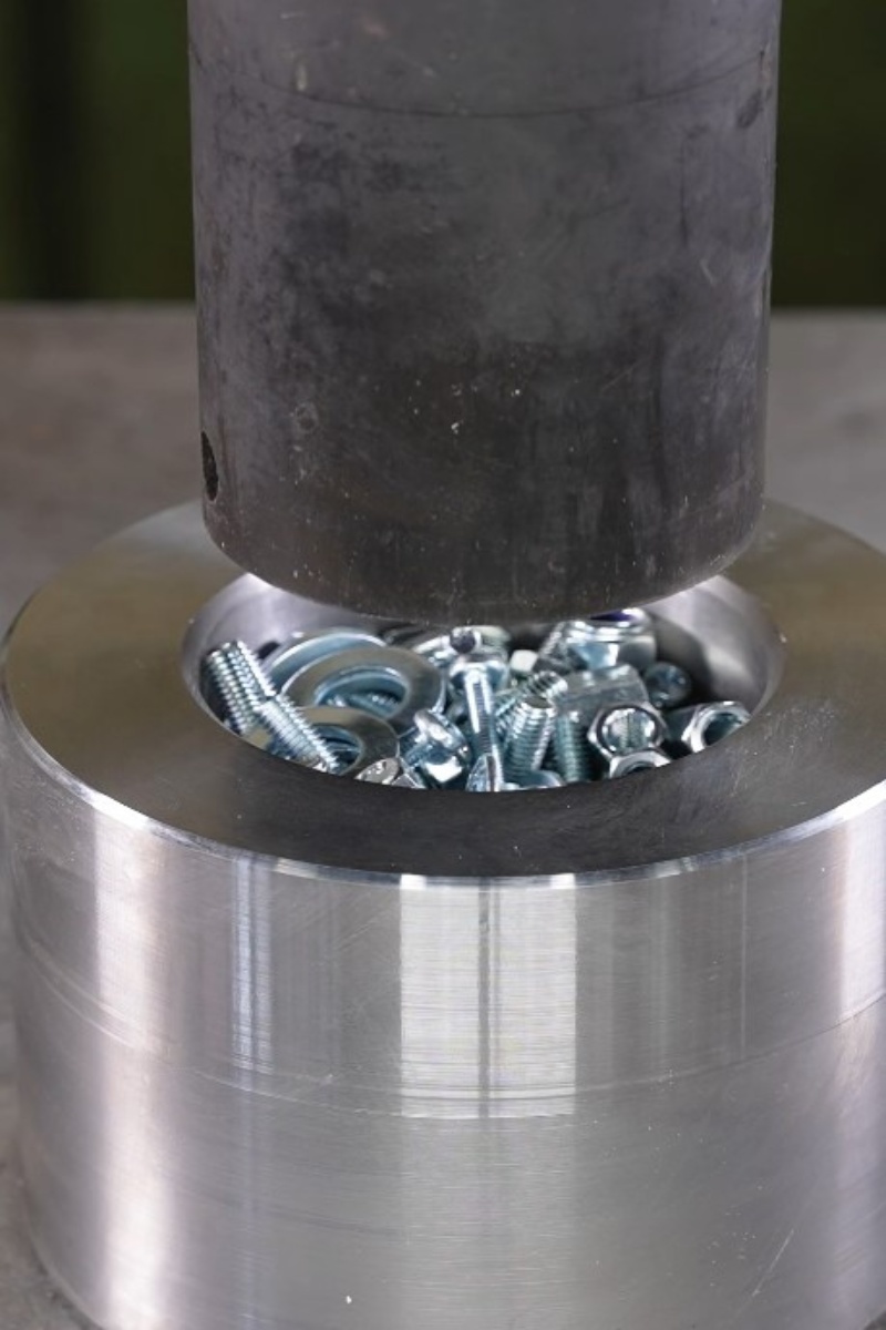 Bolts and washers crushed under powerful hydraulic press