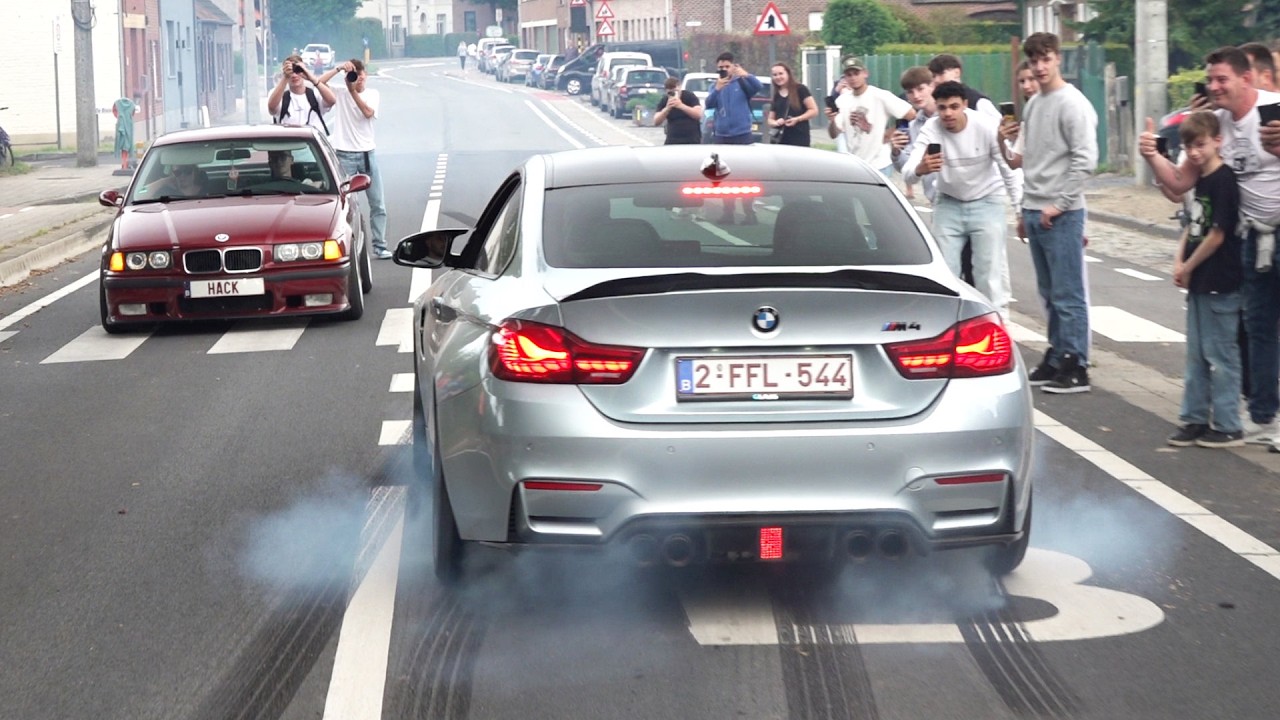 Crowd watches a BMW M4 as tire smoke fills the street