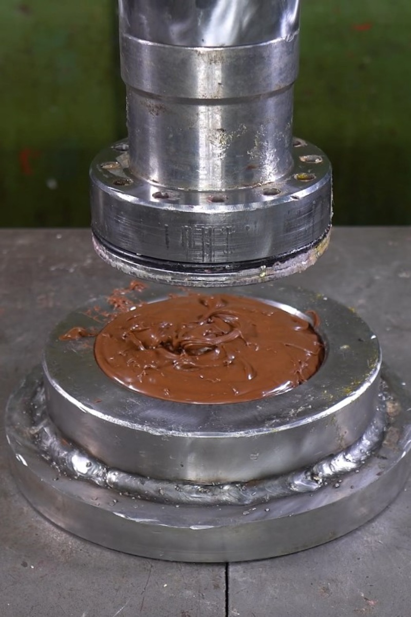 Triturar un bloque de chocolate con una prensa hidráulica
