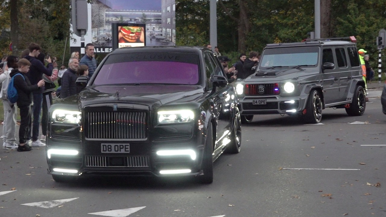 Luxury SUVs rolling slowly past spectators on a city street