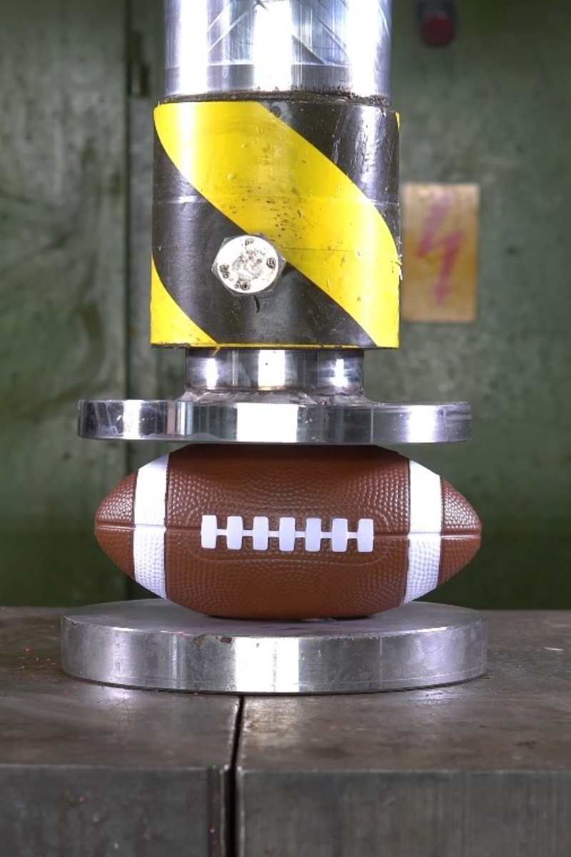 Ecraser un ballon de football américain sous une presse hydraulique