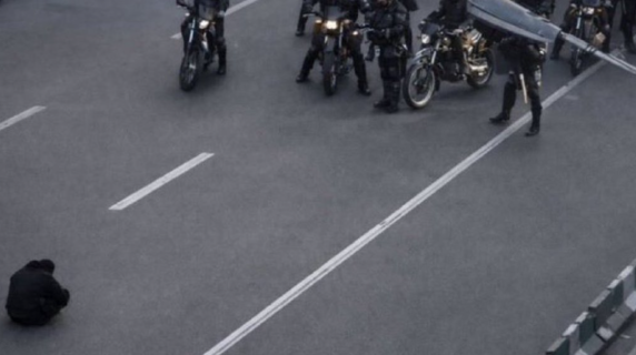 Il manifestante seduto a terra sfida la polizia durante le proteste per ...