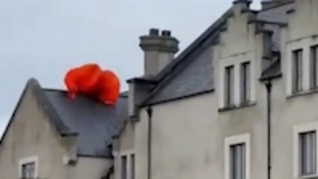 Moment paraglider botches landing and smashes into hotel roof