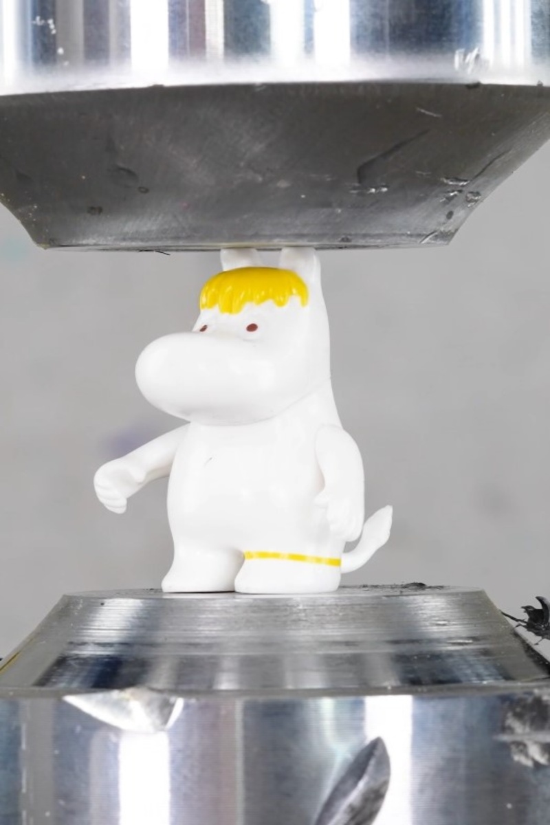Broyage d'un mignon jouet de dessin animé sous une presse hydraulique