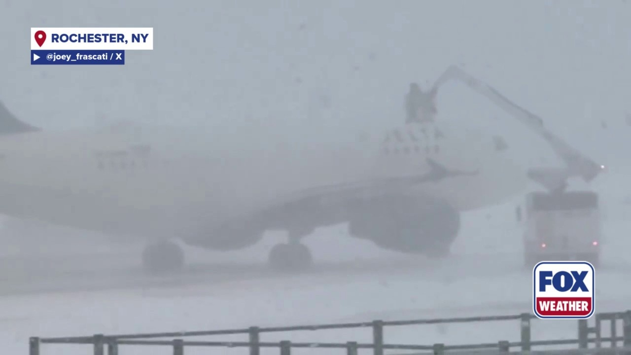 Crews work to de-ice a plane at an airport in Rochester, New York, on ...