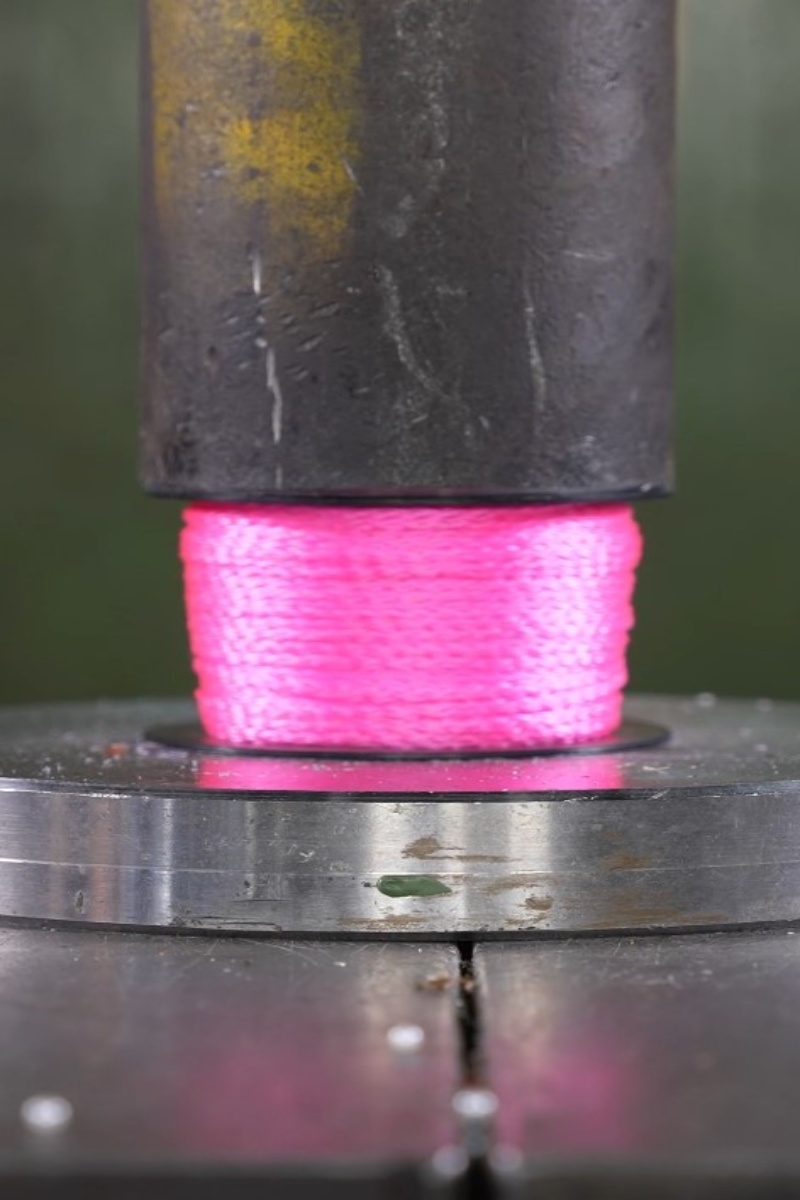 Zgniatanie różowej szpuli liny pod prasą hydrauliczną