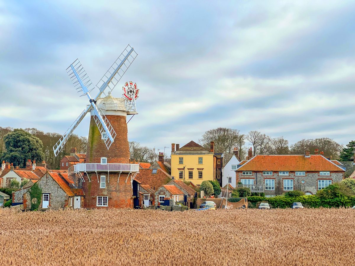 The pretty flint seaside village with Flemish gables, water meadow and ...