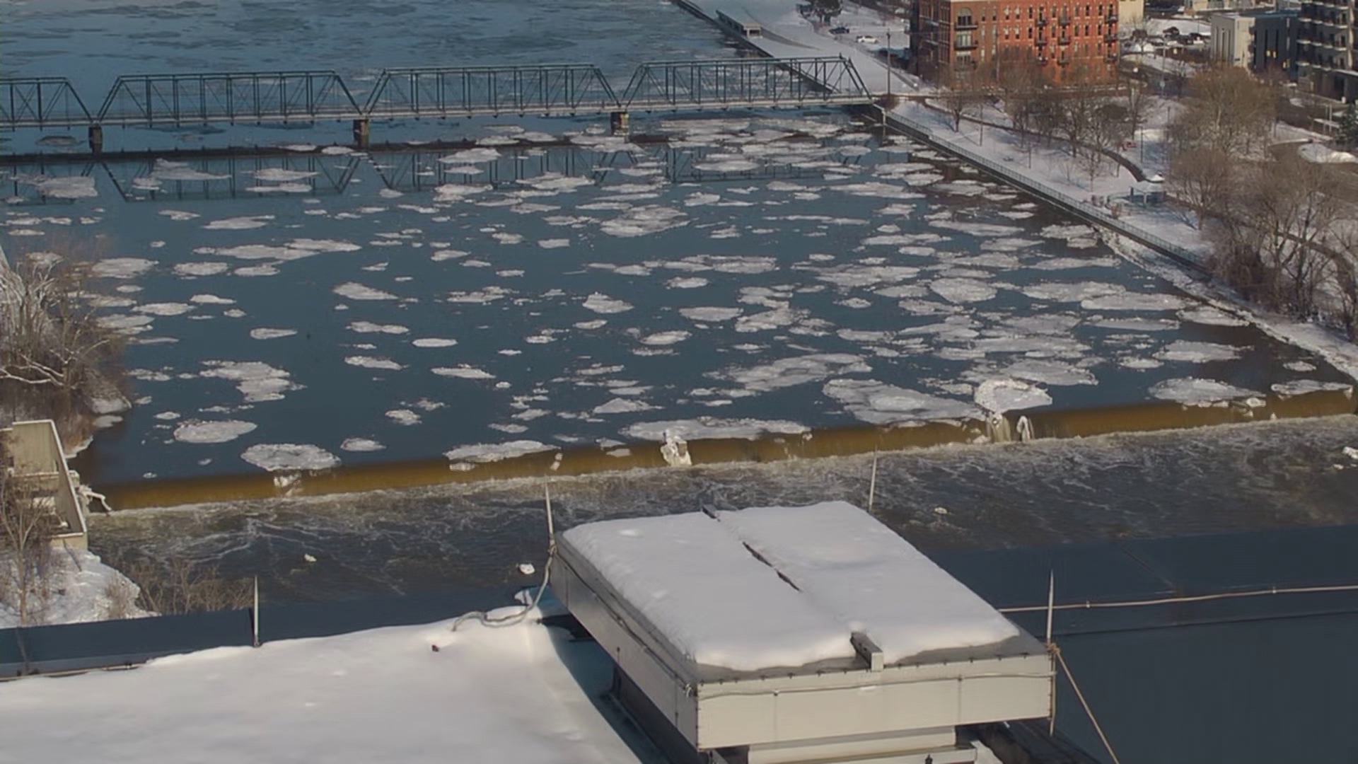 Watch ice chunks fall over a dam along the Grand River
