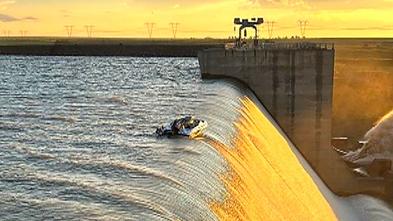 Una lancha queda suspendida en una presa mientras varios hombres se ...