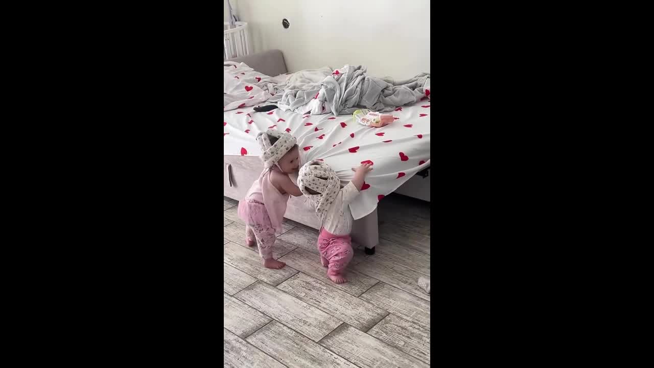 Twin babies playfully tussle with helmets in Simferopol, Russia