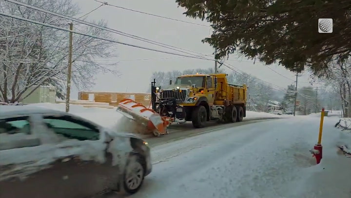 A snow plow passes by as it clears a snowy New Brunswick street