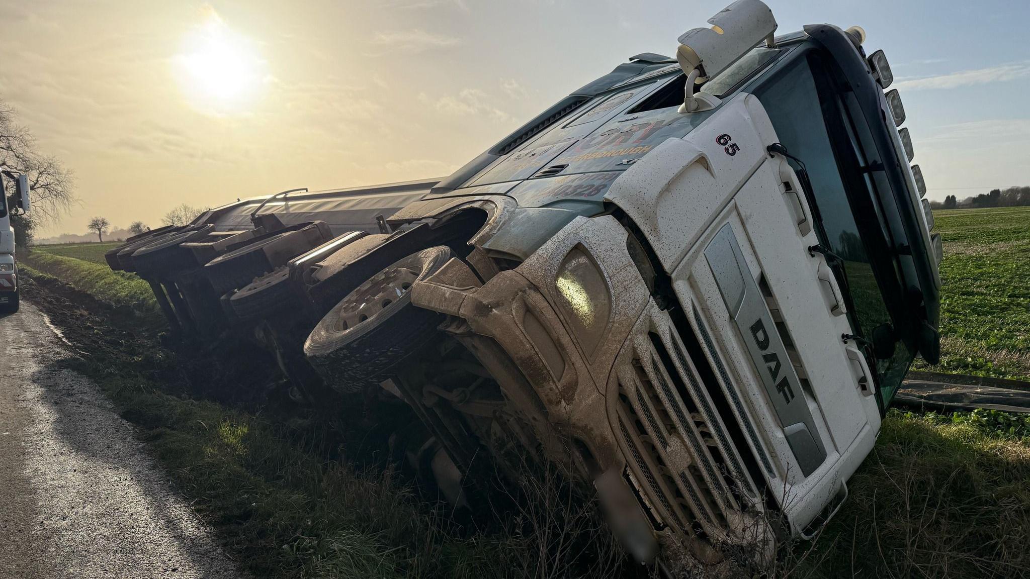 Road closed after lorry overturns into ditch