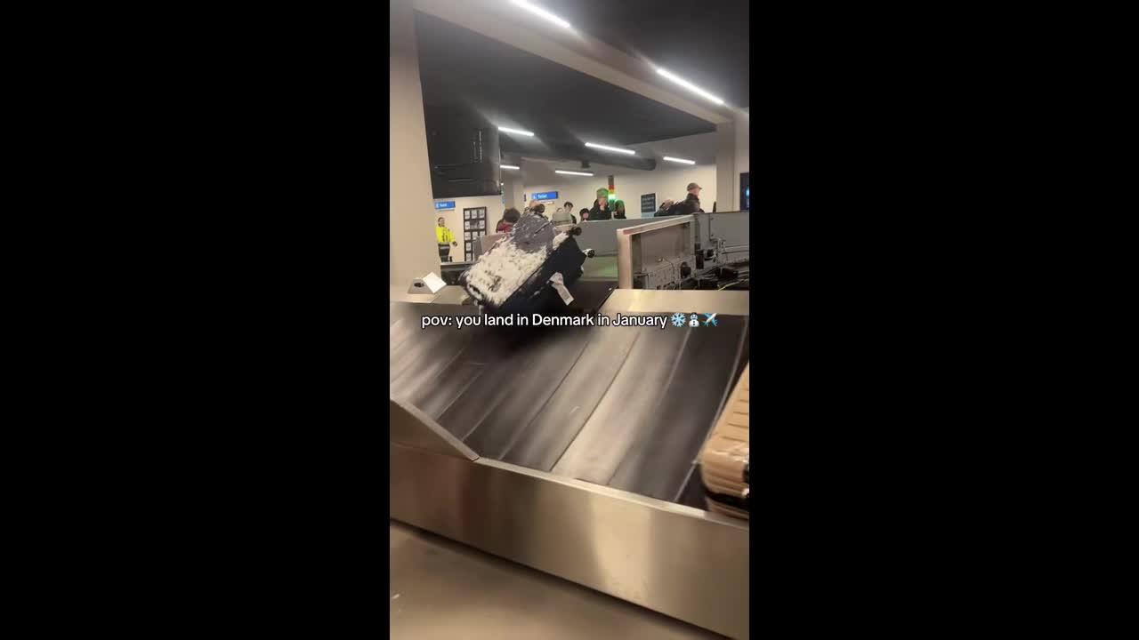 Suitcases covered in snow as tourists collect luggage at Danish airport
