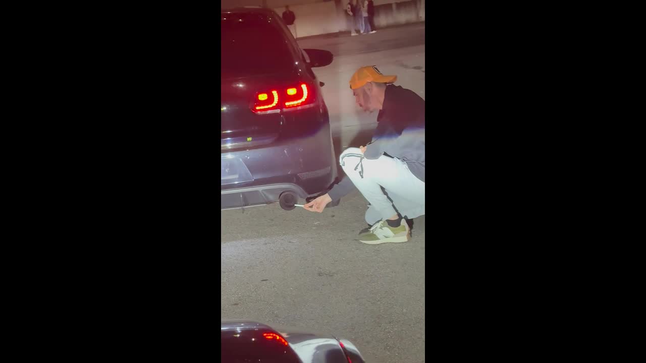 Man lights a cigarette using car exhaust flames in Porto, Portugal
