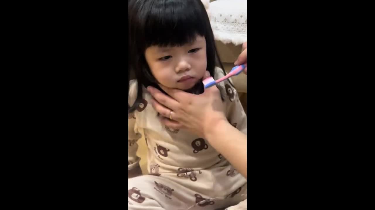 Daughter lets dog brush her teeth in Batam, Indonesia