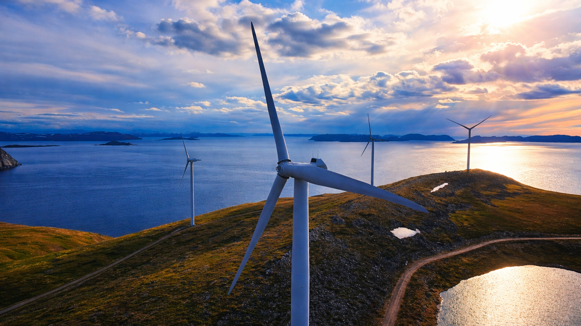 Turbines turning slowly beside a quiet blue sea