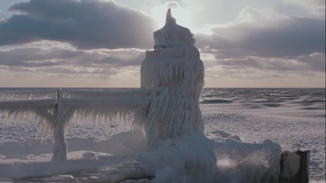 Waves batter ice-covered lighthouse on Lake Michigan