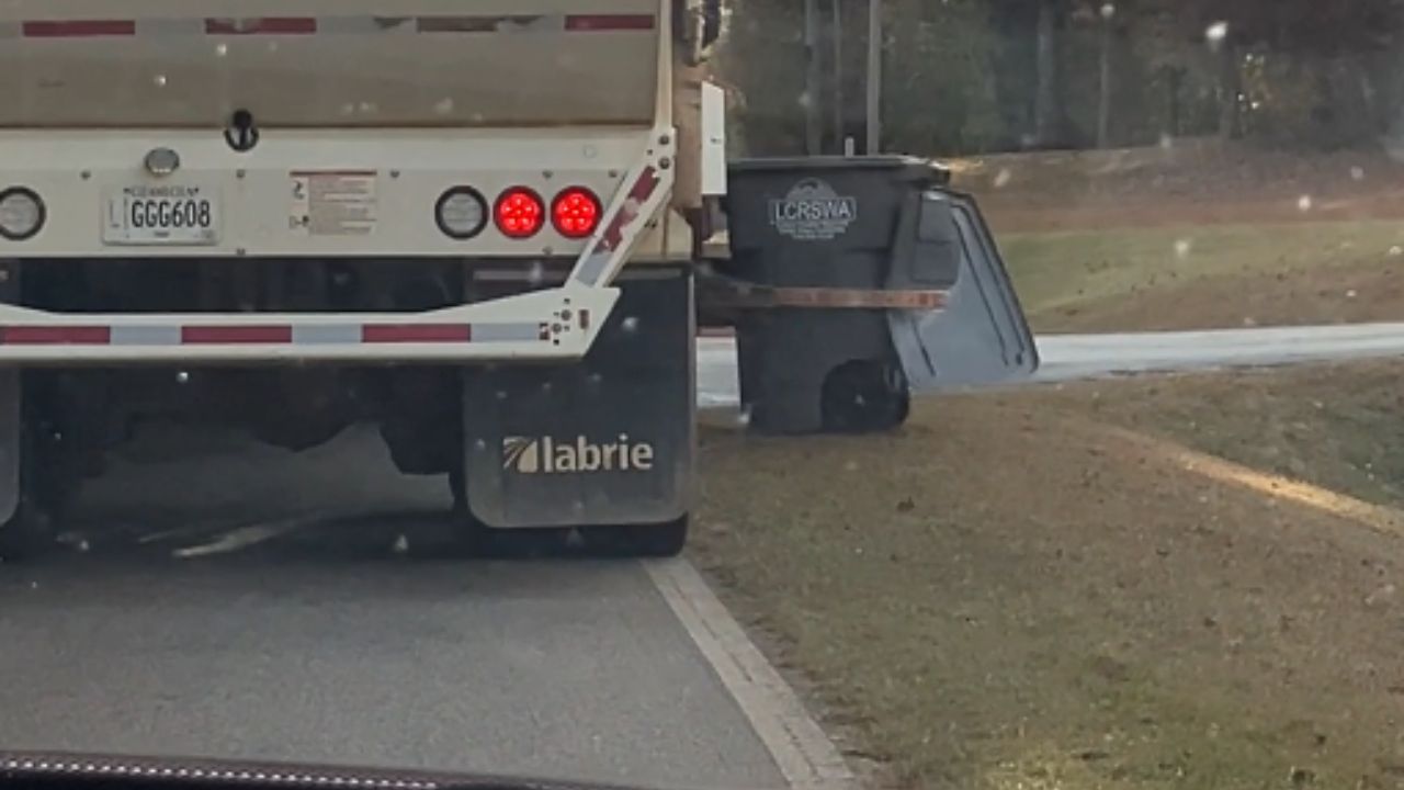 Trash truck operator struggles to set a bin upright and ends up ...