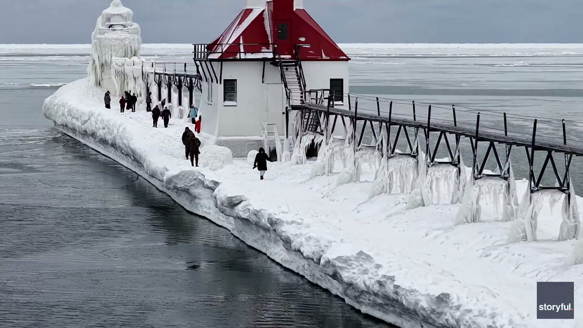 Drone footage captures people walking on ice-covered pier despite warnings