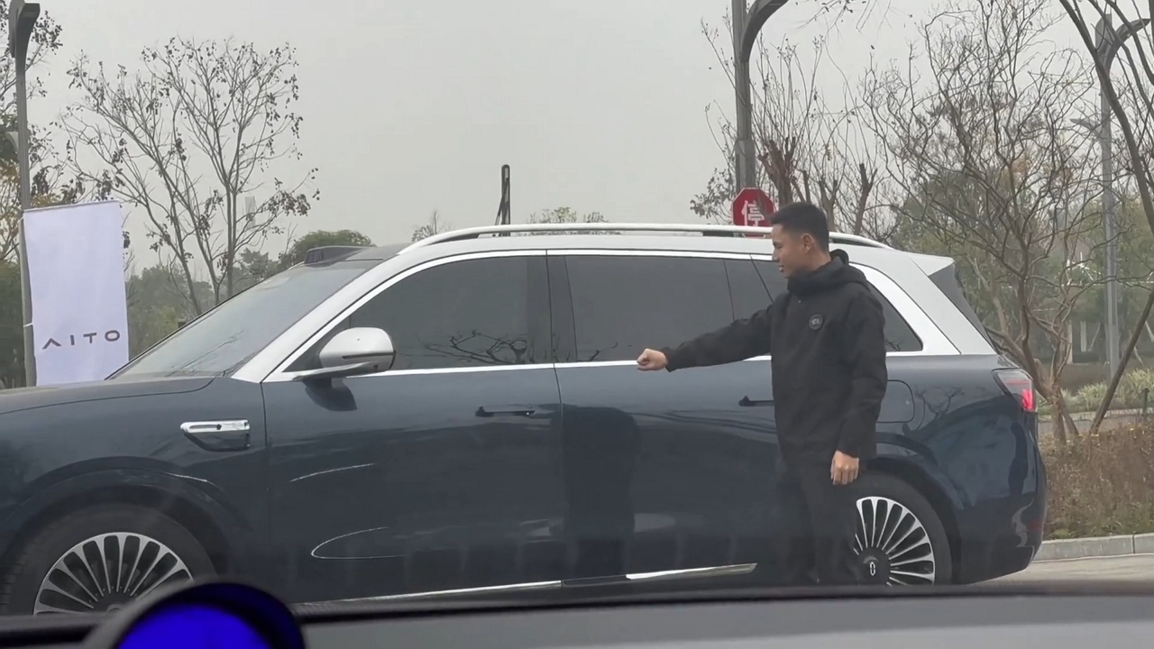 Man humorously controls car with hand gestures beside AITO M9 in ...