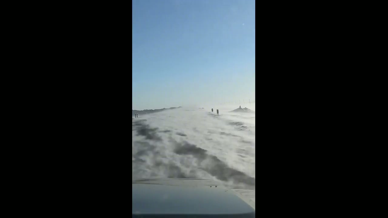 Wind-driven snow sweeps across roadway in wave-like patterns in Karamay ...