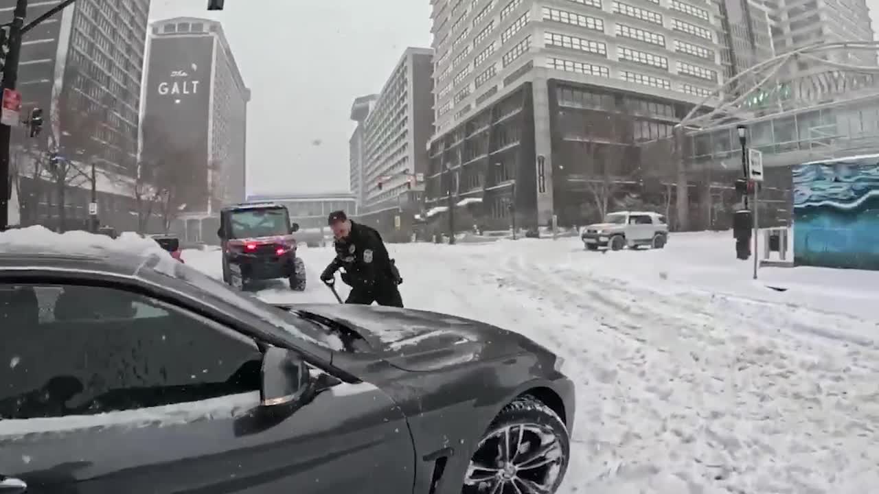 Police officers rescue car trapped in snow in Louisville