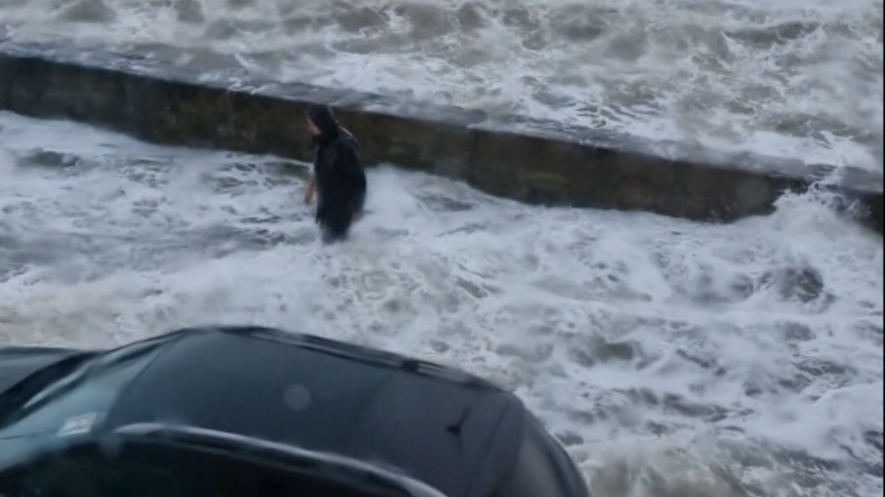 Man's risky attempt to clear a drain as floodwaters surge during Storm Bram
