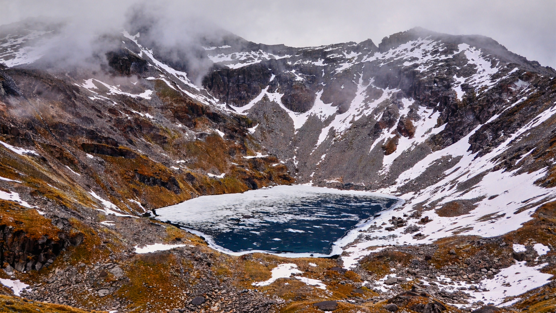 Jagged rock walls and mist around an alpine lake