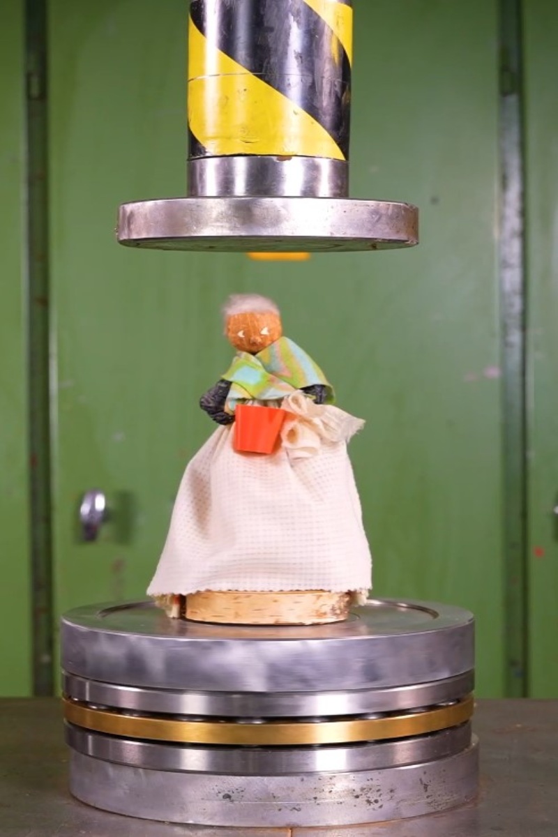 Figura di bambola in legno sotto pressa idraulica