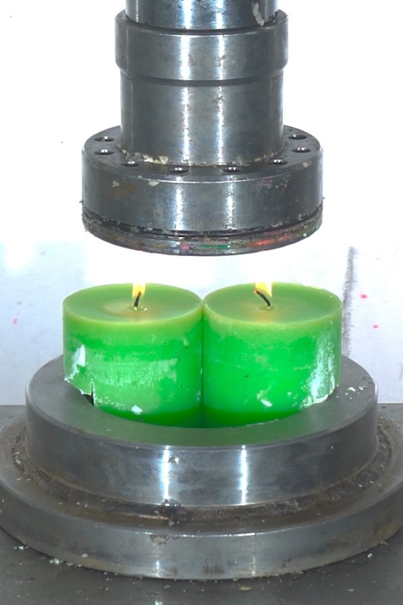 Crushing two burning candles under hydraulic press