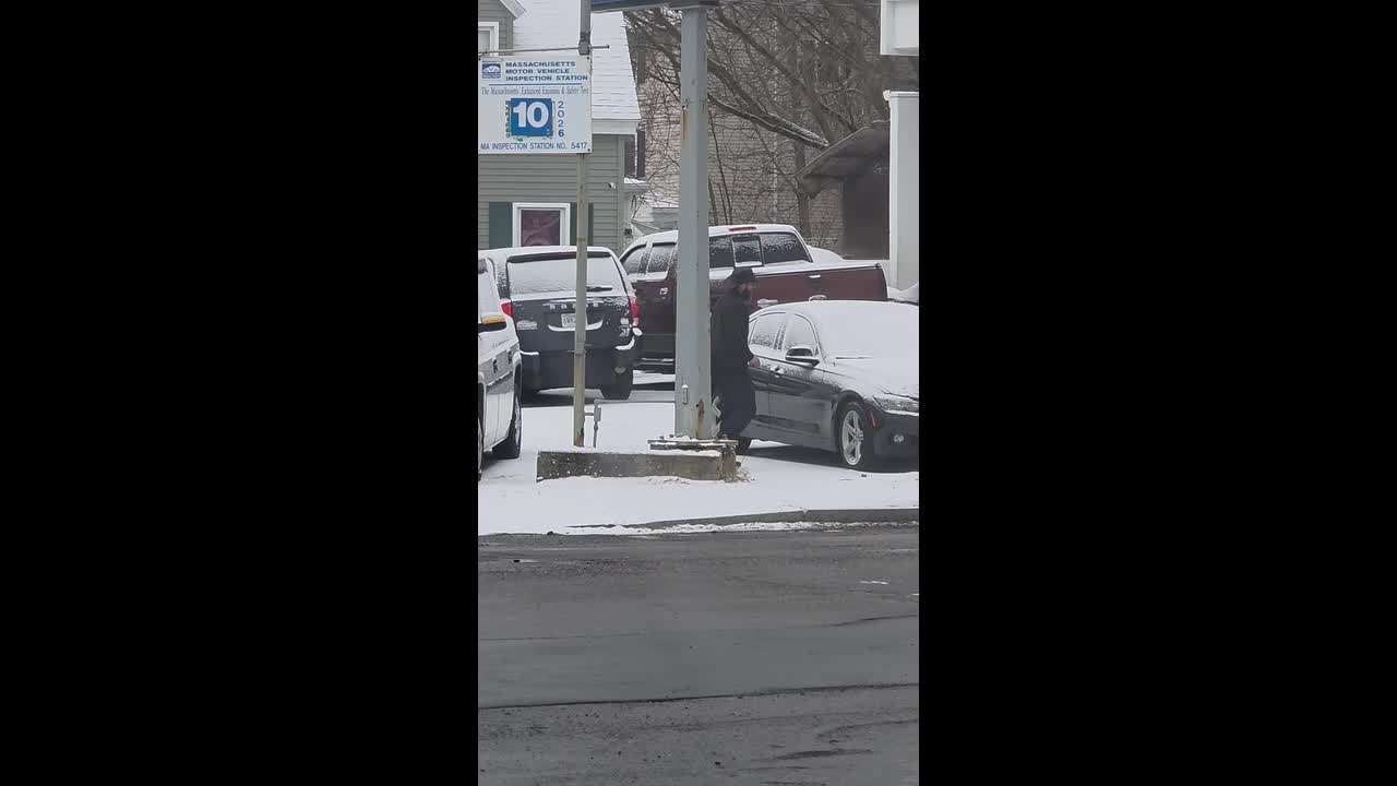 Man draws smiley faces on snow-covered cars in Peabody, Massachusetts, USA