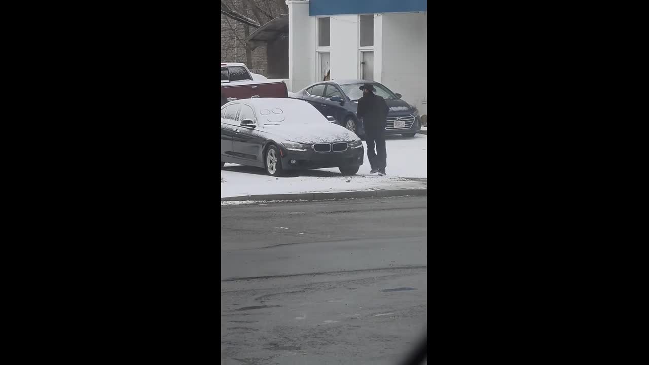 Man draws smiley faces on snow-covered cars in Peabody, Massachusetts, USA