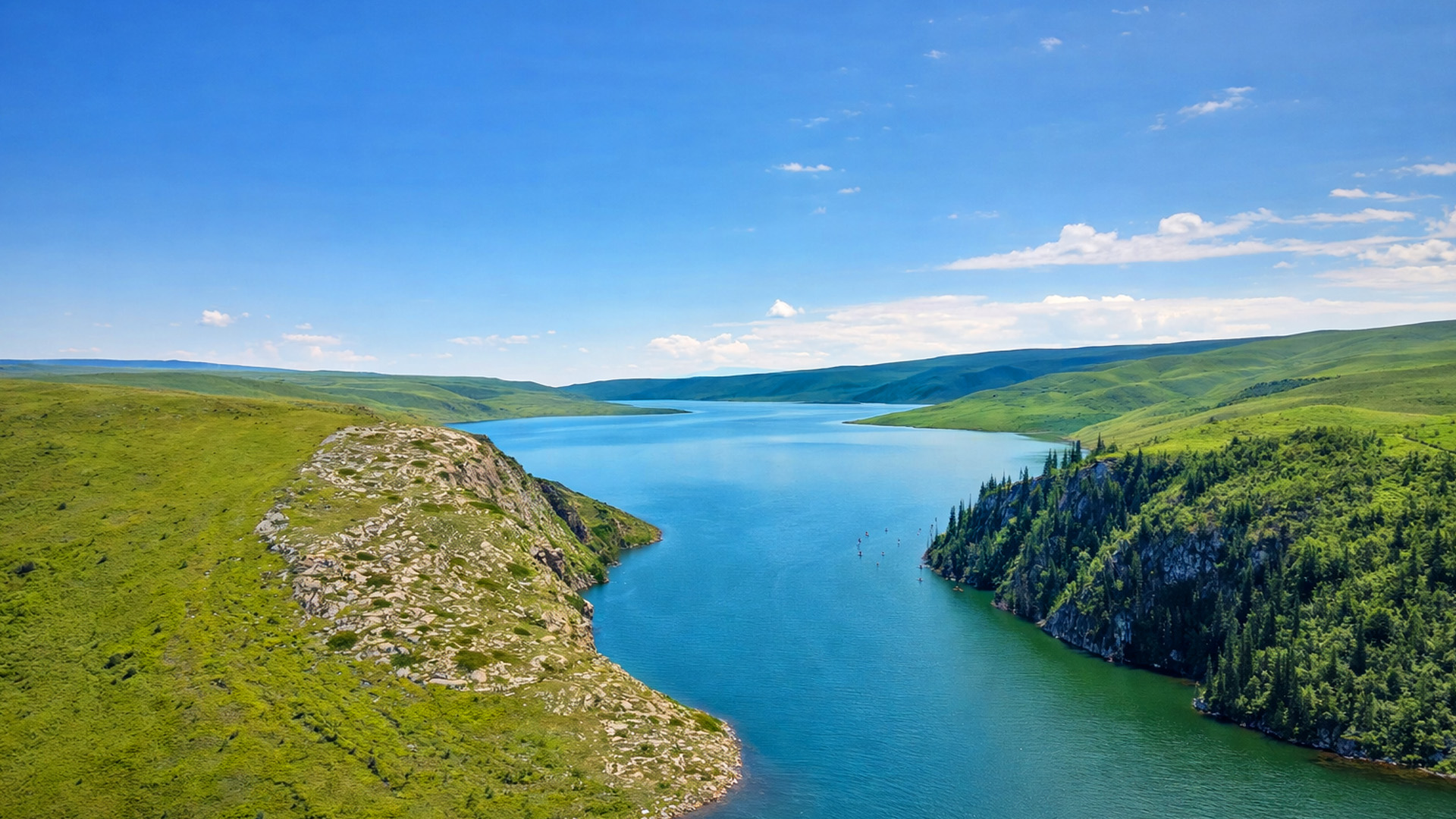 Blue water between grassland and forest