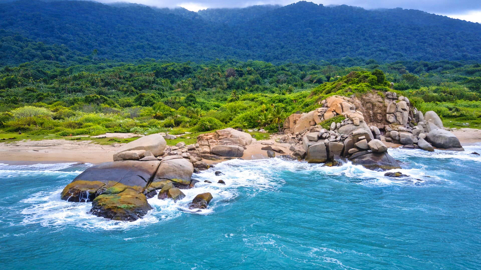 A natural beach backed by dense green hills